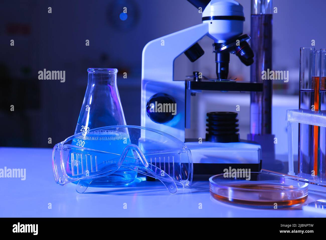 Test tube, conical flask and safety goggles on table in medical ...