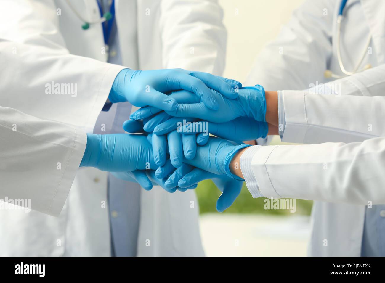 Group of doctors putting hands together in clinic Stock Photo - Alamy