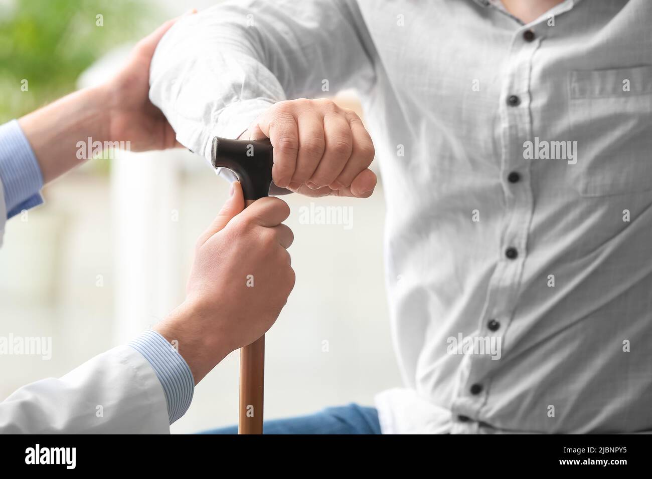 Doctors helping patient with cane in clinic Stock Photo - Alamy