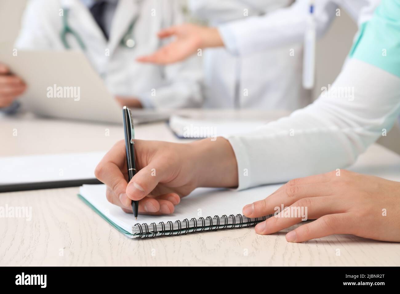 Doctor writing in notebook during meeting in clinic Stock Photo - Alamy