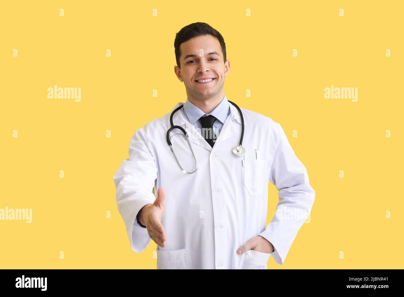 Male doctor giving hand for shake on yellow background Stock Photo - Alamy