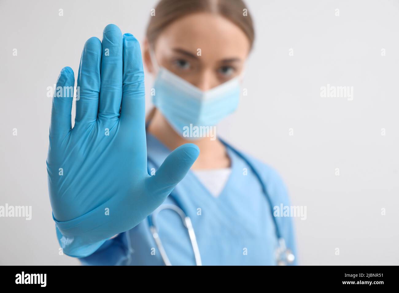 Female nurse showing STOP gesture on light background Stock Photo - Alamy