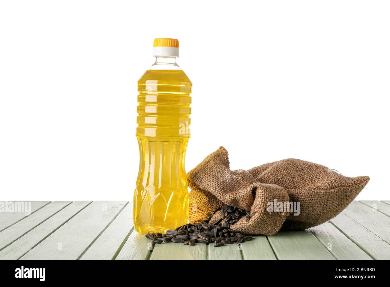 Bottle of oil, sack bag and sunflower seeds on color wooden table ...
