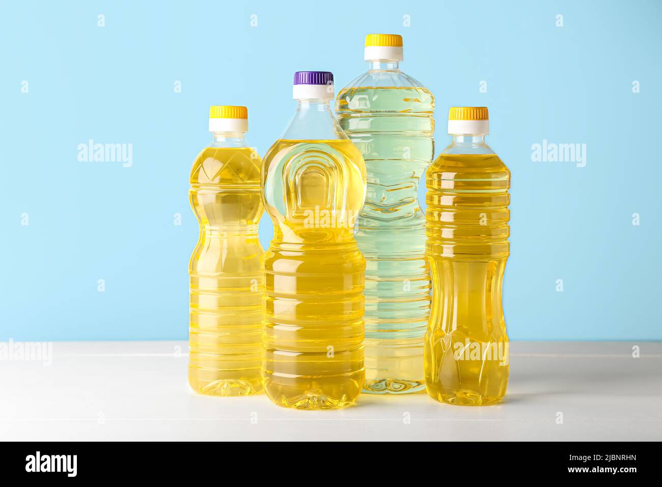 Bottles of sunflower oil on table against blue background Stock Photo ...