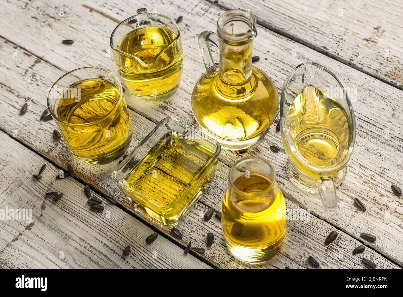 Glass containers and sunflower seeds on white wooden background Stock ...