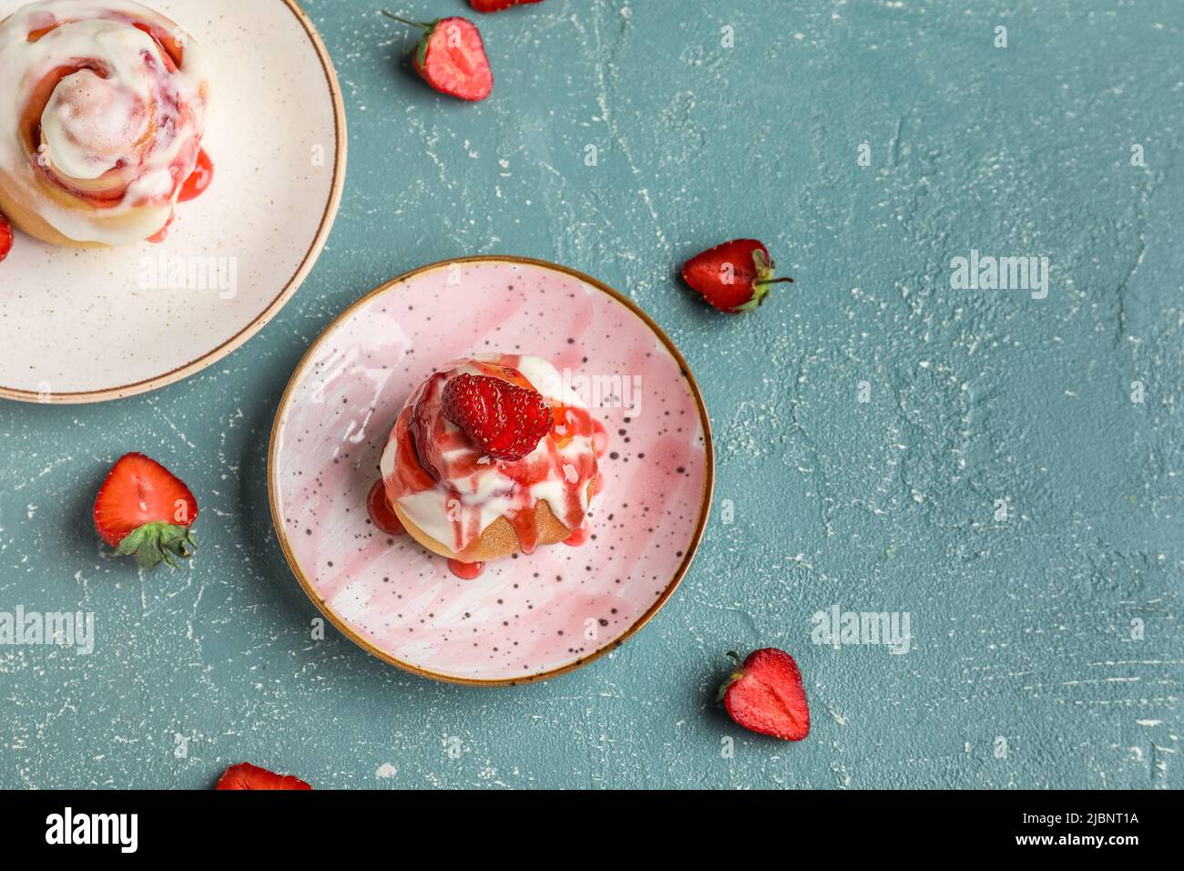 Plates with strawberry cinnamon rolls on color background Stock Photo ...