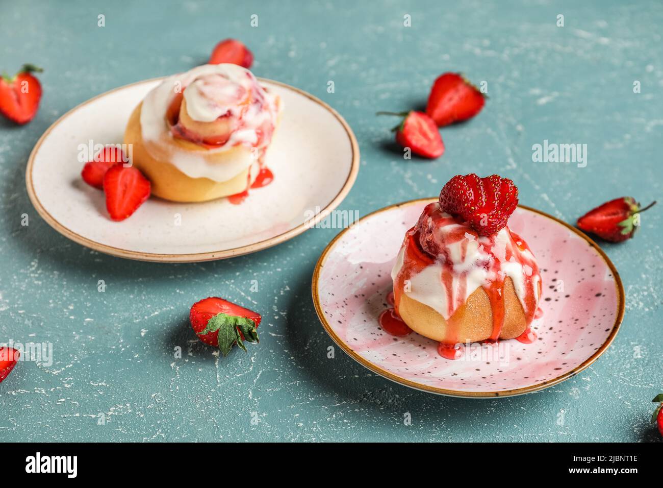 Plates with strawberry cinnamon rolls on color background Stock Photo ...