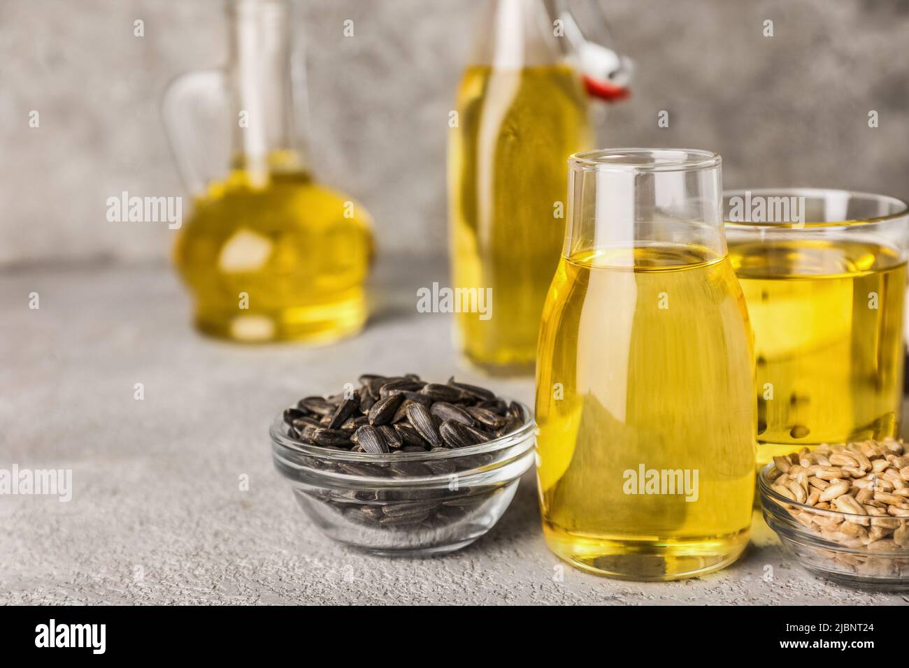 Glass containers with oil and bowls of sunflower seeds on grunge ...