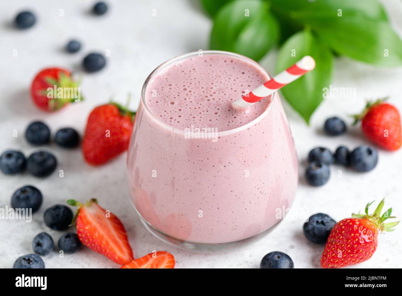 Pink strawberry and blueberry vegan smoothie in glass, closeup view ...