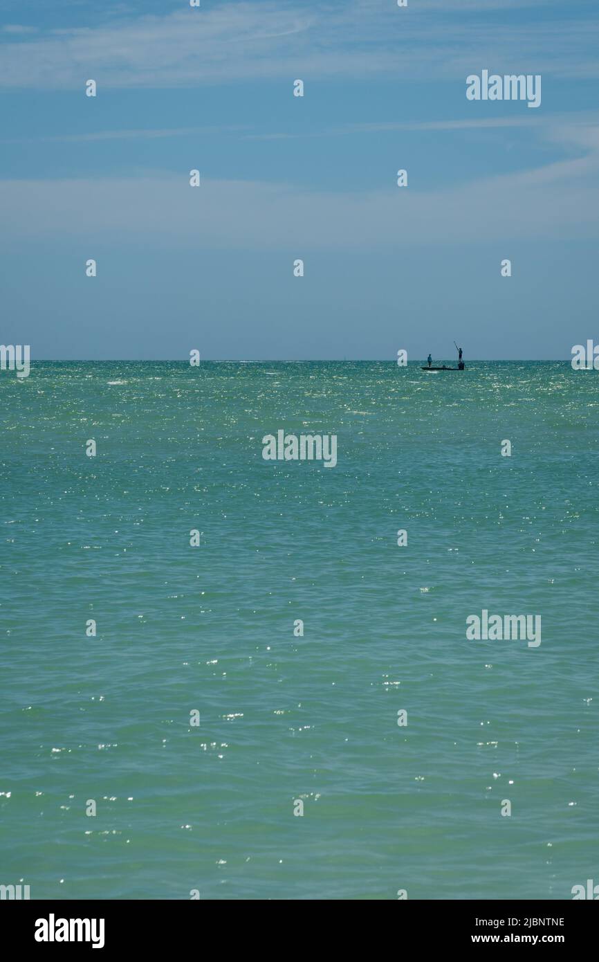 Silhouette of row boat in distance on beautiful blue ocean with copy ...