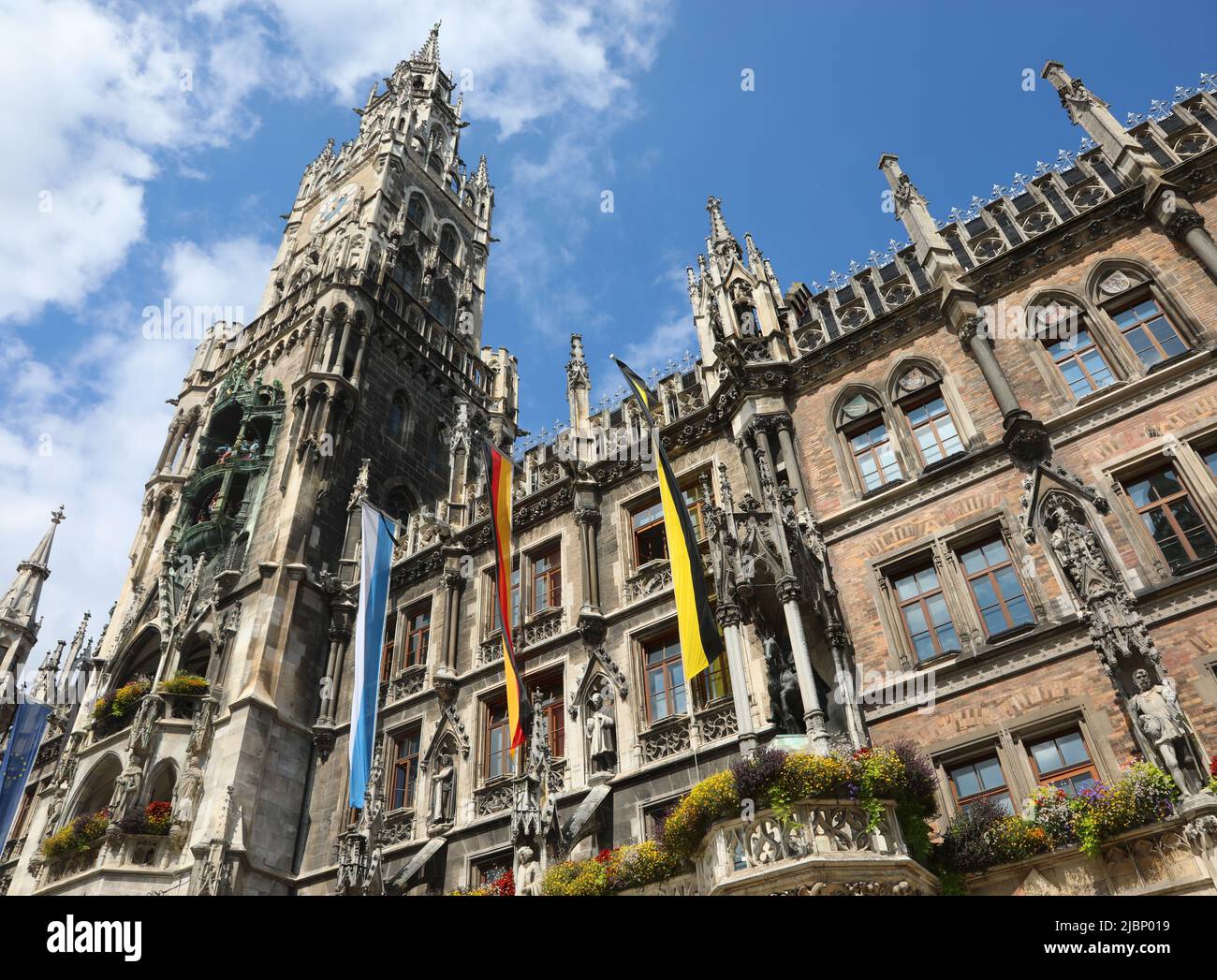 Clock tower of the Town Hall of Munich in Germany and the flags on of ...