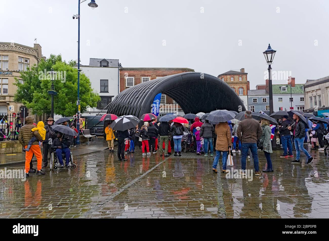 People in the rain at an outdoor concert being held in the marketplace ...