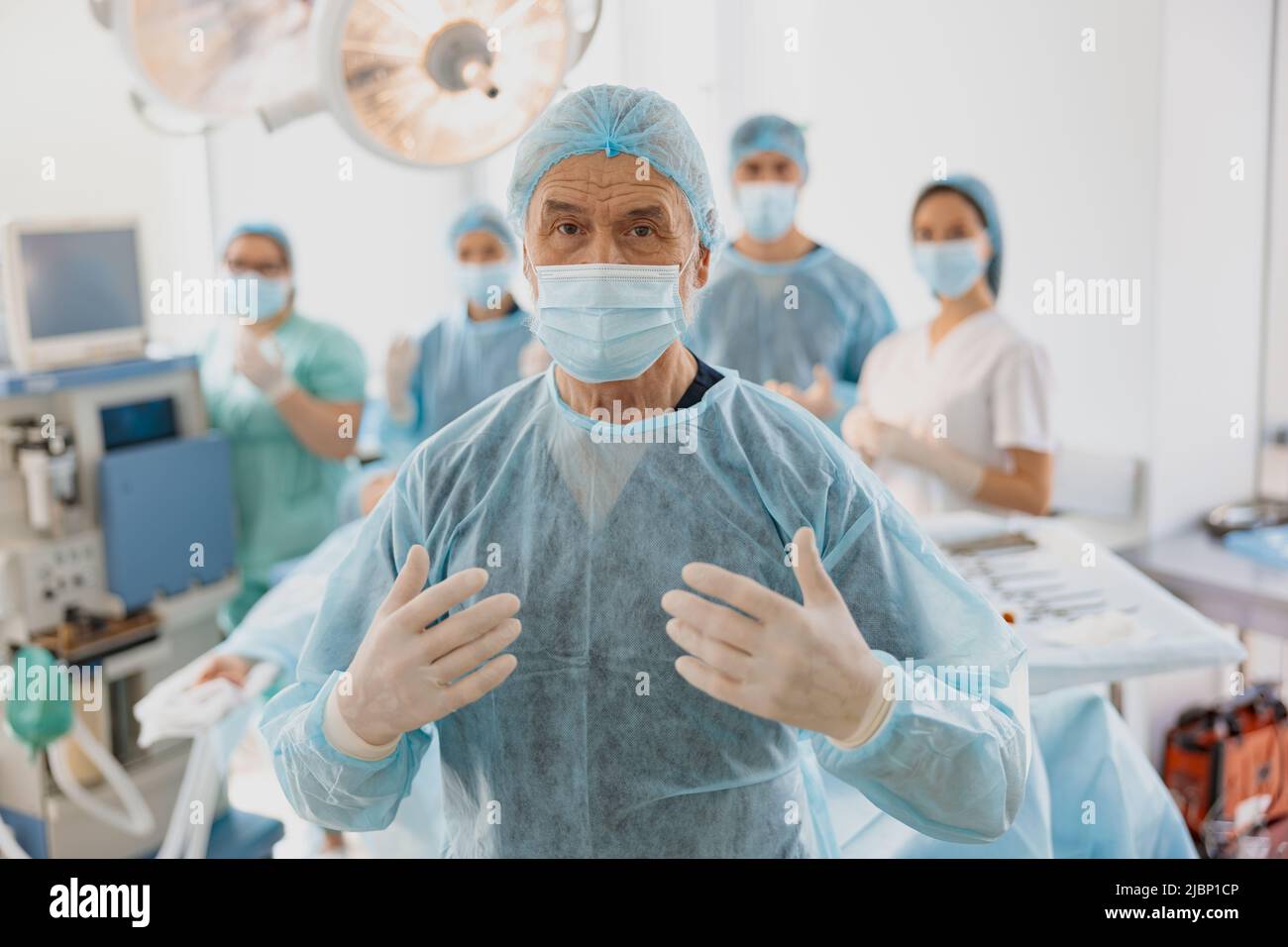 Portrait of senior surgeon standing in operating room, ready to work on ...