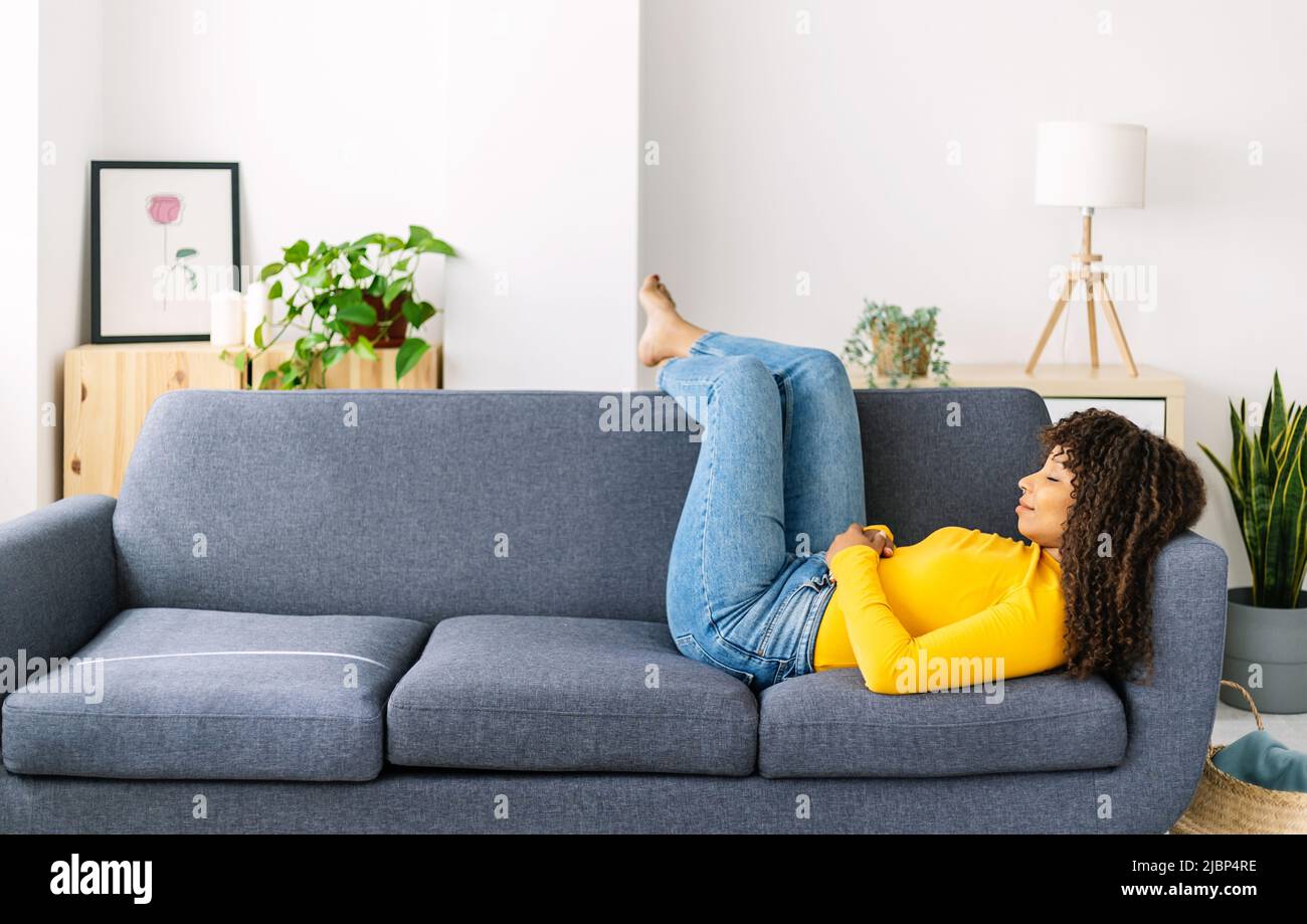 Young woman relaxing on sofa at home Stock Photo - Alamy