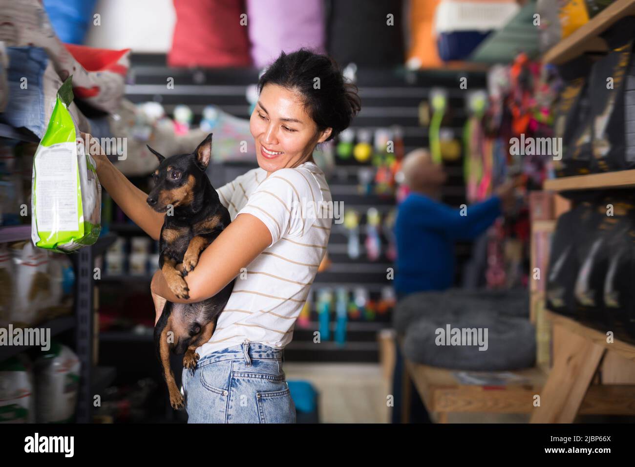 Happy female customer with dog choosing dry food in pet shop Stock ...