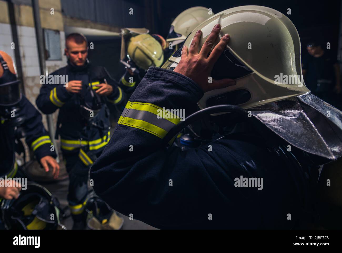 Group of firefighters standing inside the fire brigade wearing helmet ...