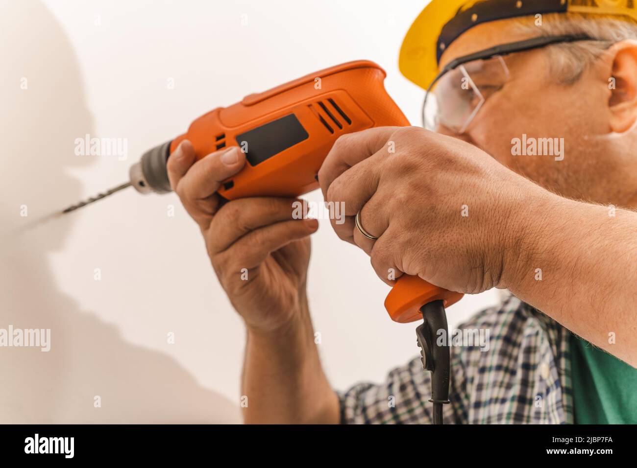 Construction Worker drilling a hole with a drill on a white wall. Copy ...