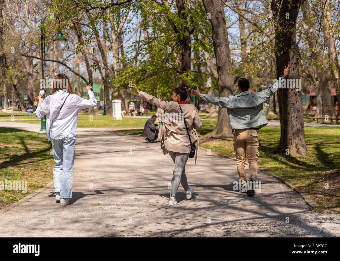 Full body happy women and man in casual outfits walking in summer park ...