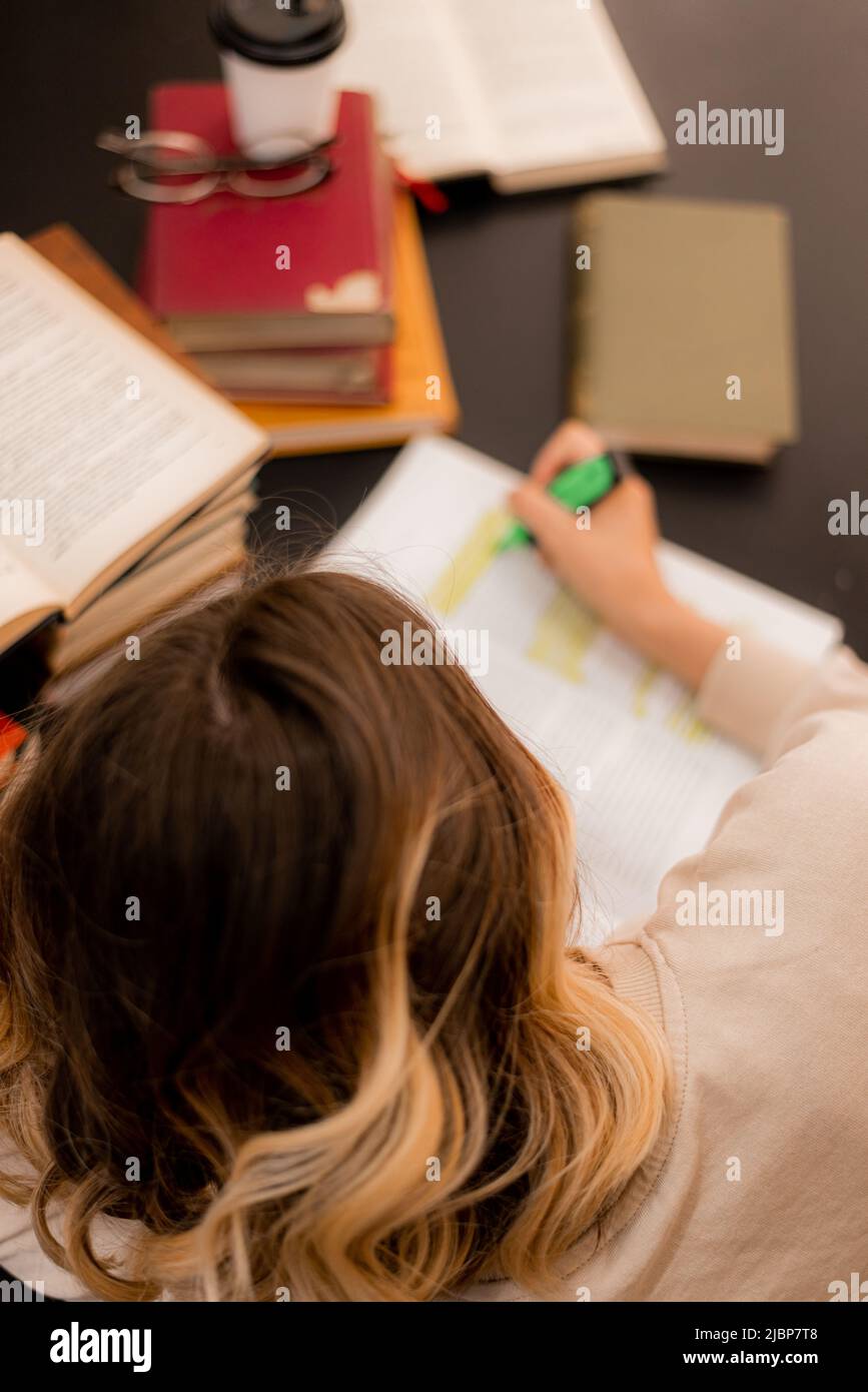 Girl underlining the important part in a college book while sitting on ...