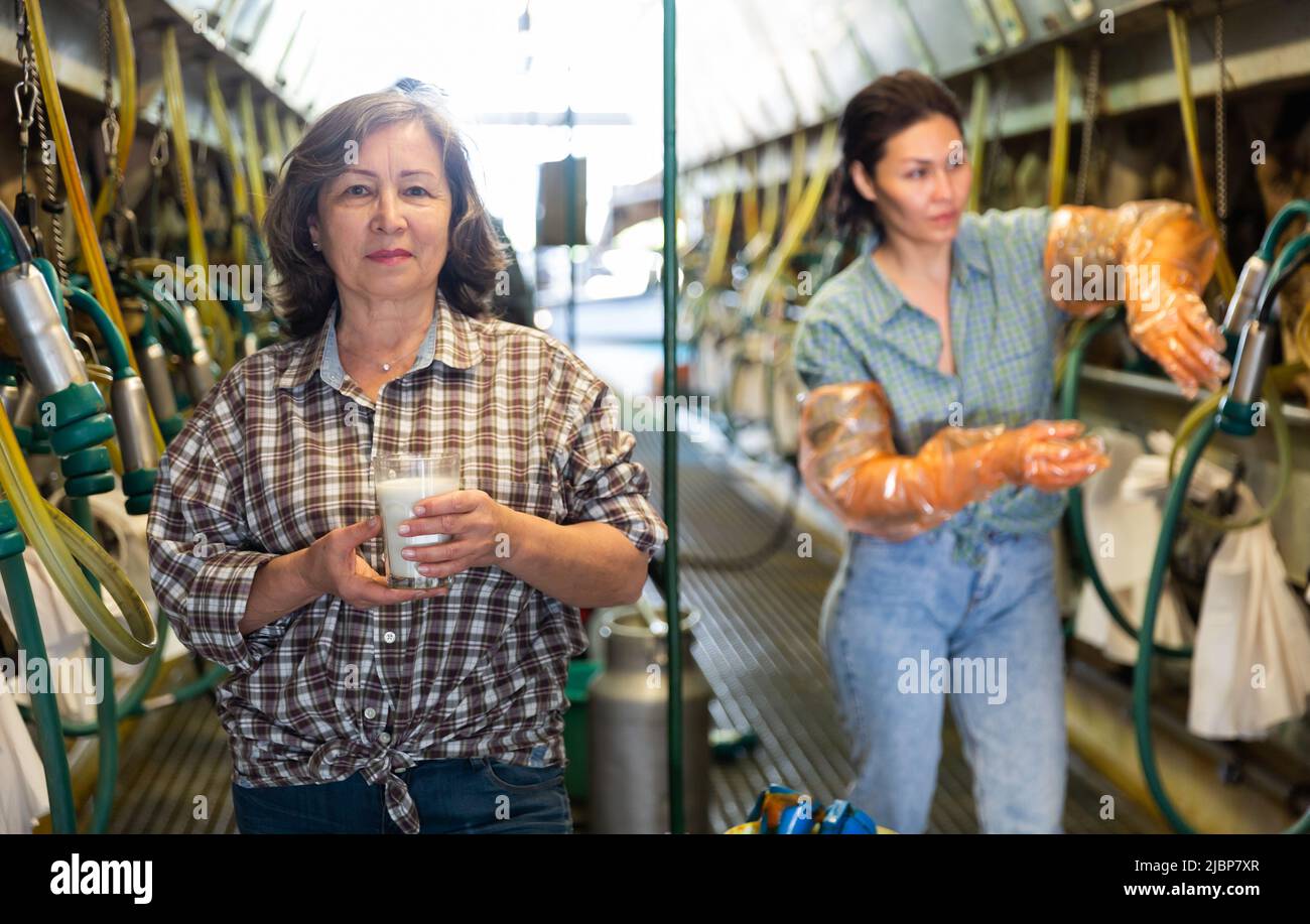 Woman with milk glass near milking line Stock Photo - Alamy