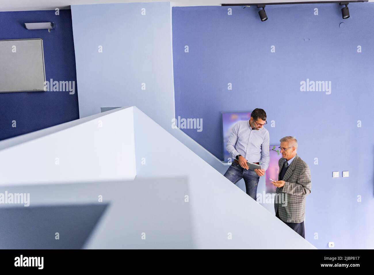 Two senior businessmen are standing on the stairs together Stock Photo ...