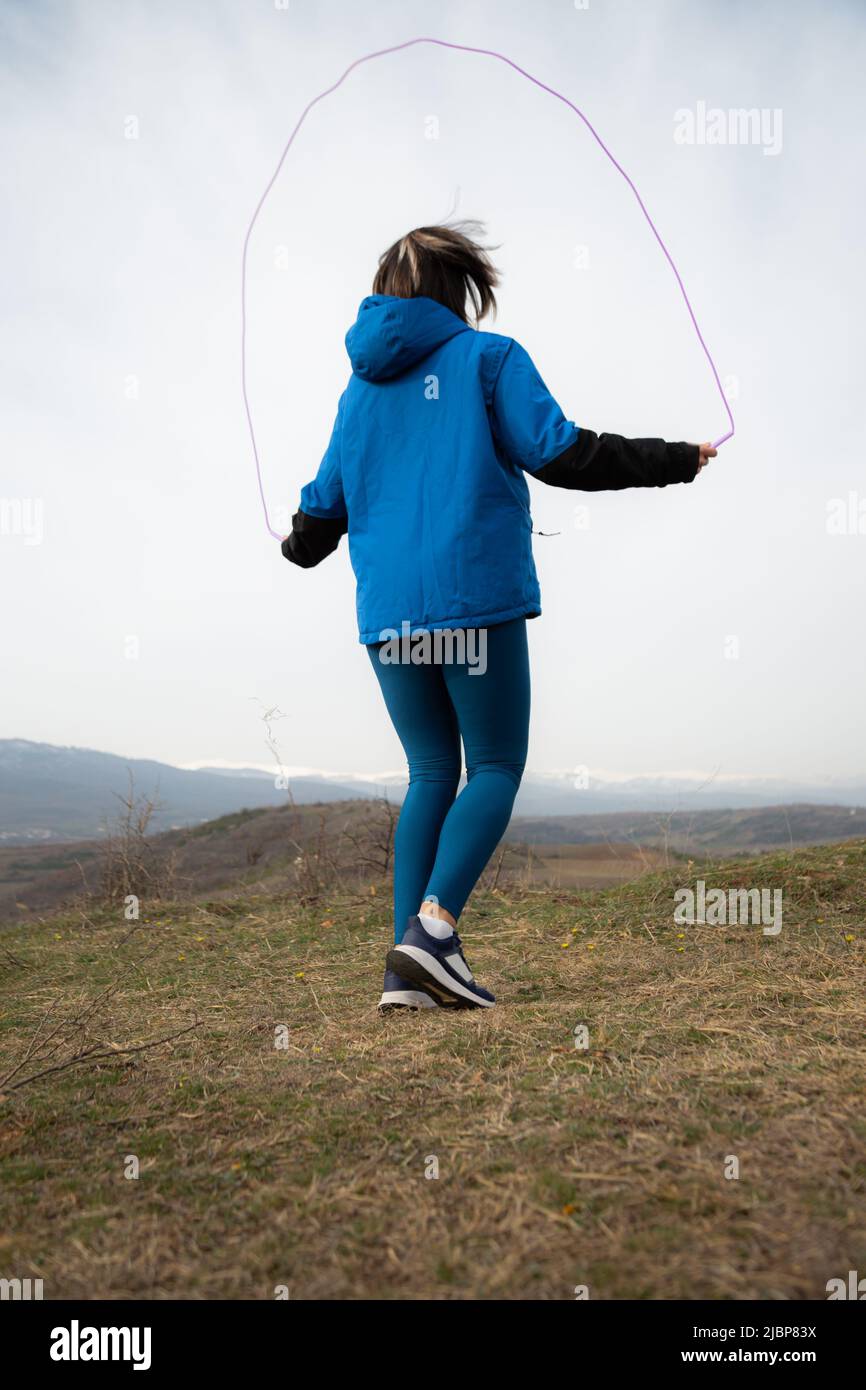 Amazing and active woman is doing a jumping rope exercise in the forest ...