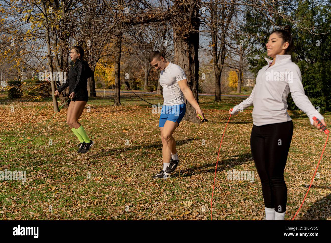 Three attractive and beautiful fit friends are jumping on the rope and ...