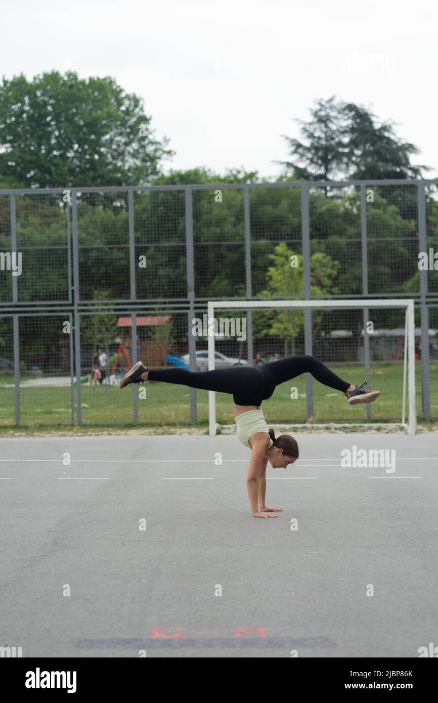 Adorable and beautiful youn girl is balancing on her hands while doing ...