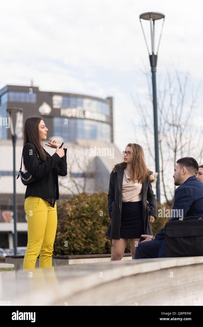 Group of young business people are sitting and talking outside while ...