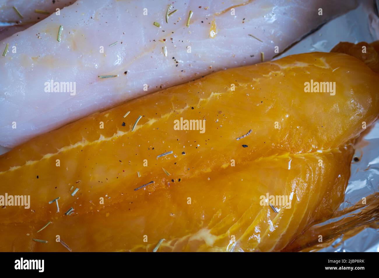 Raw seasoned fish fillets on baking tray closeup Stock Photo - Alamy