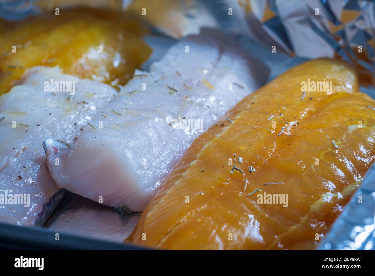 Raw seasoned fish fillets on baking tray closeup Stock Photo - Alamy