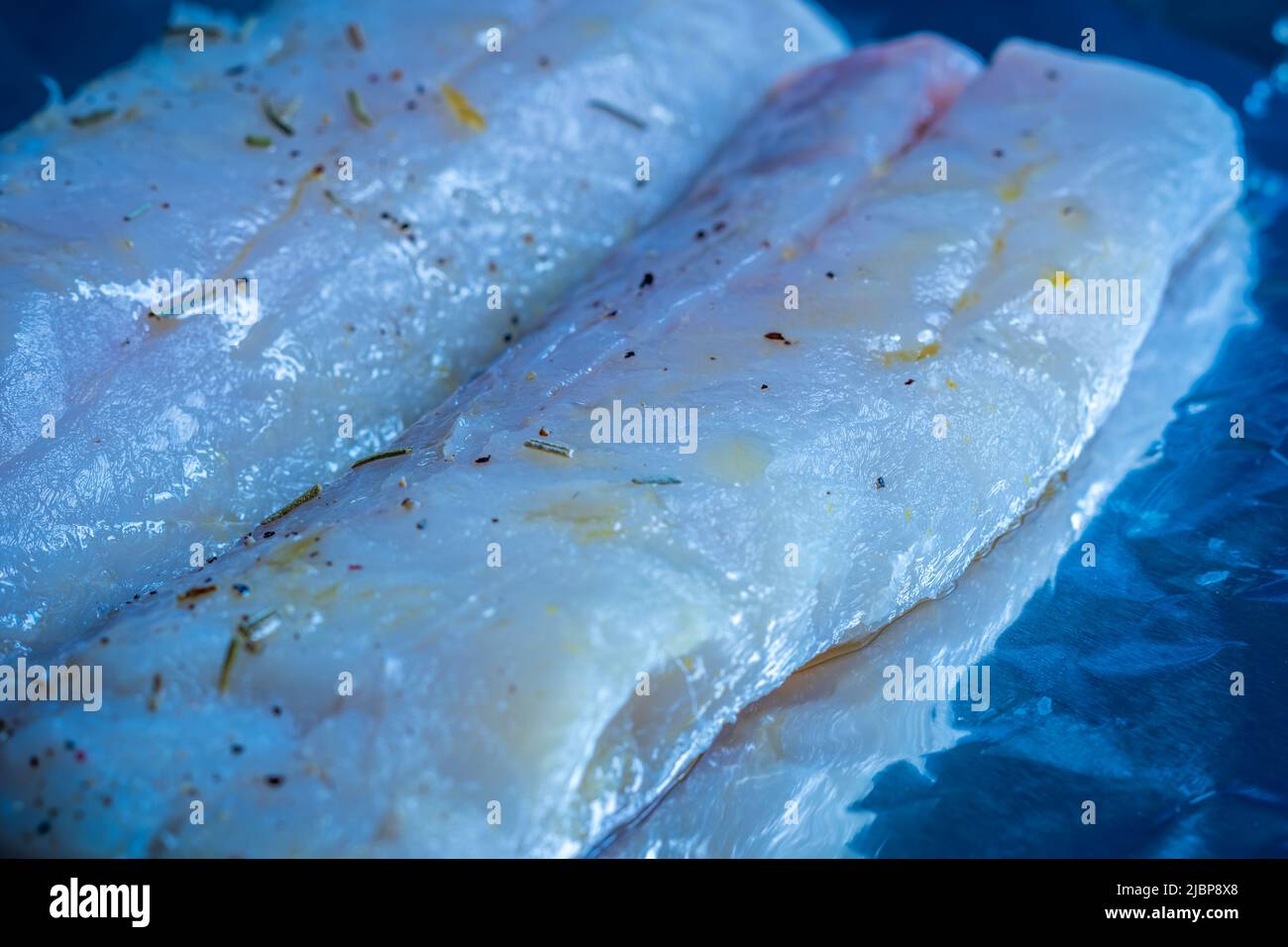 Raw seasoned fish fillets on baking tray closeup Stock Photo - Alamy