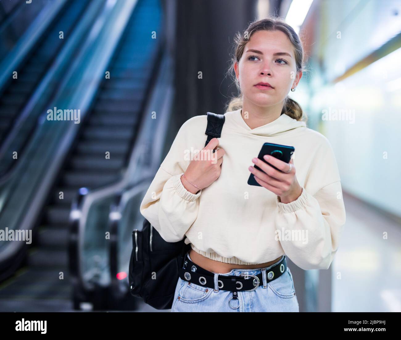 Portrait of a focused girl standing near the escalator in the subway ...
