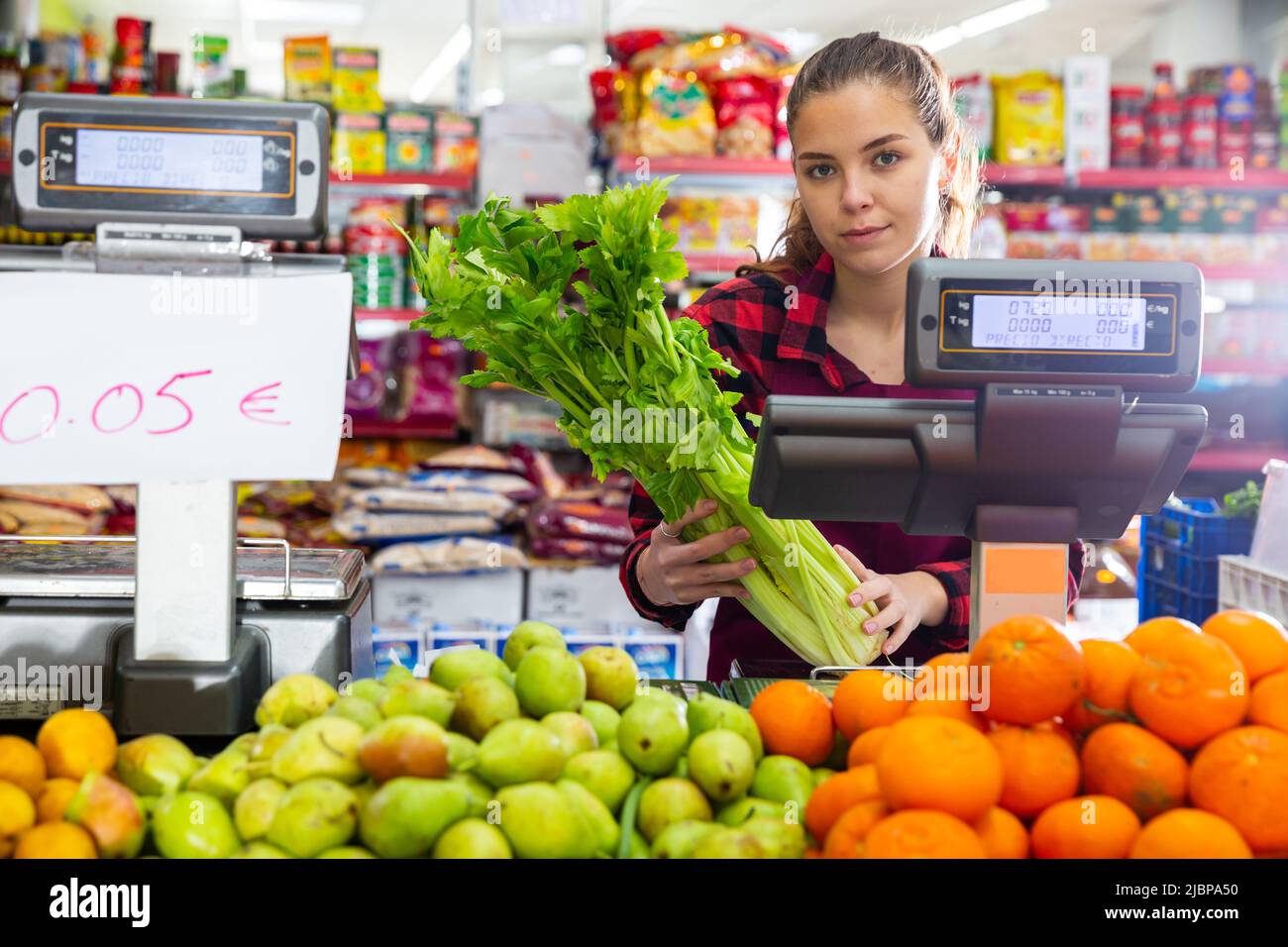 Smiling european female seller weighing celery Stock Photo - Alamy