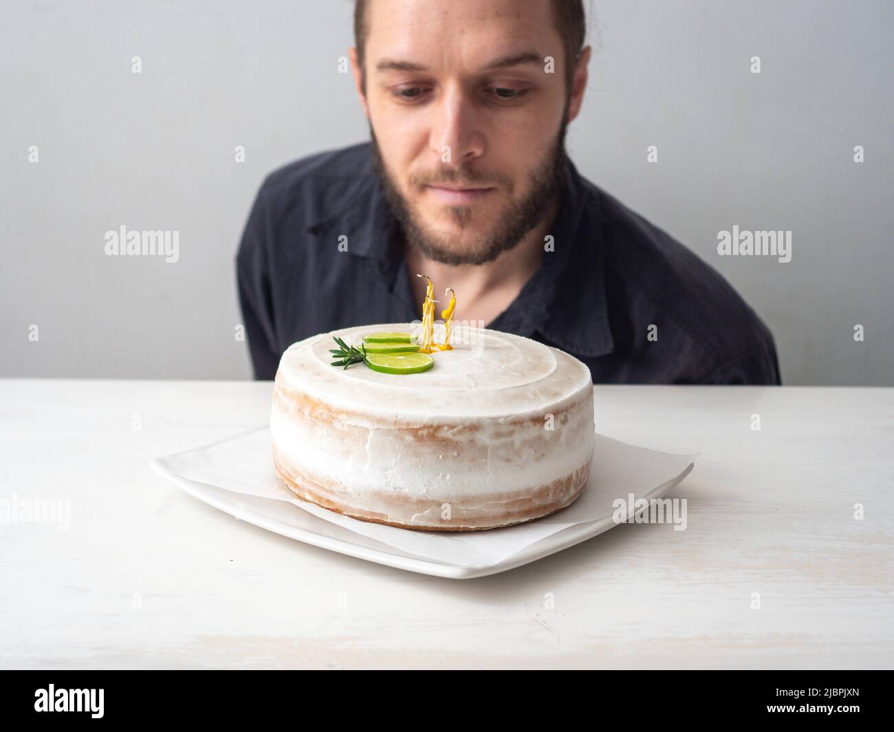 White Man Looks the Yellow Candles on a Vegan Birthday Cake with Almond ...