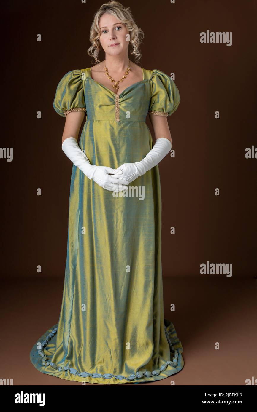 A Regency woman wearing a green shot silk dress and standing against a ...