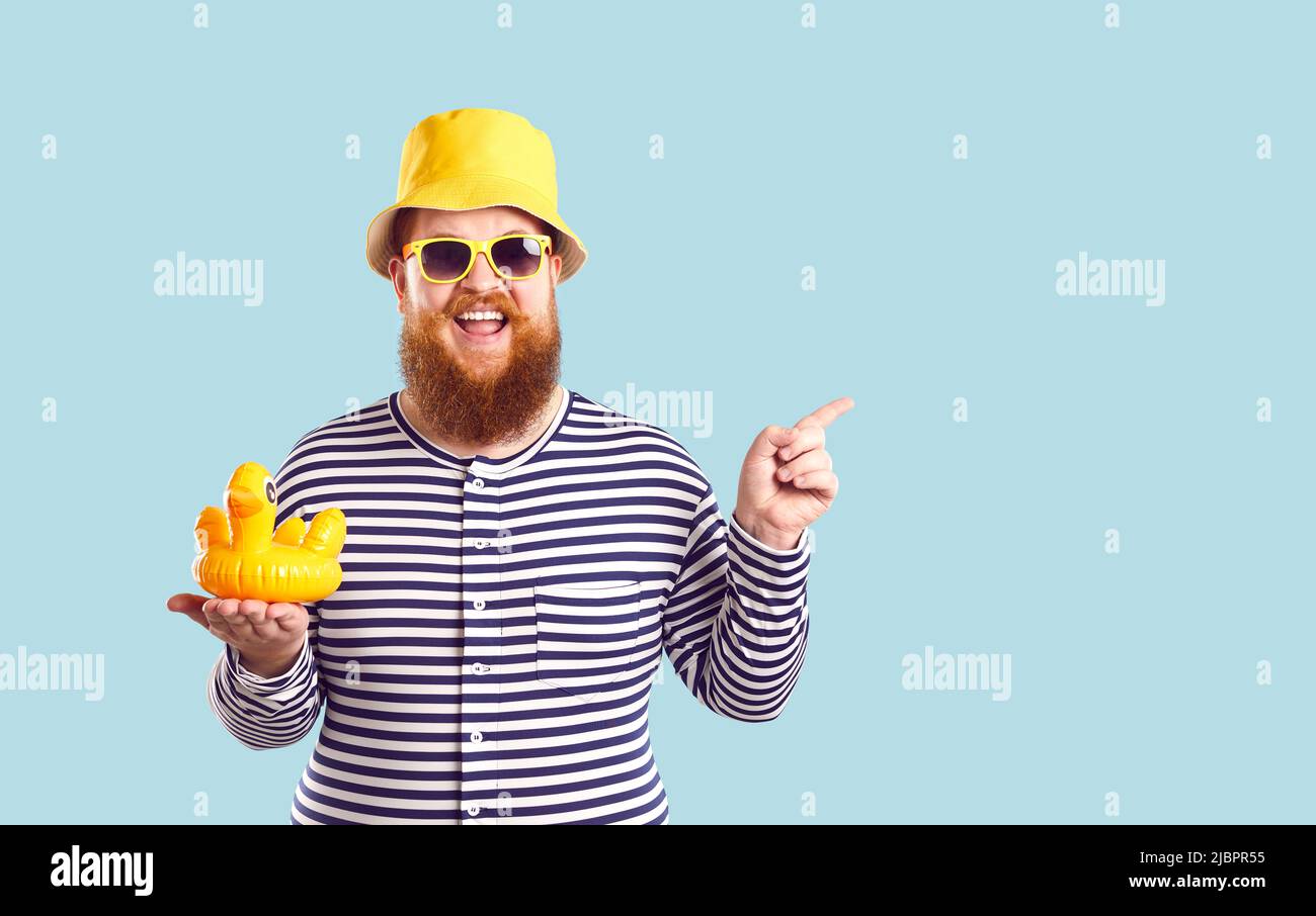 Funny fat man with inflatable duck in his hand points to copy space on ...