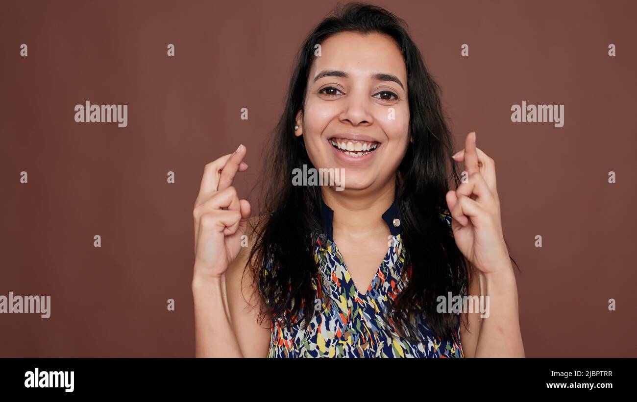Young adult feeling hopeful about wish praying for good luck, posing ...