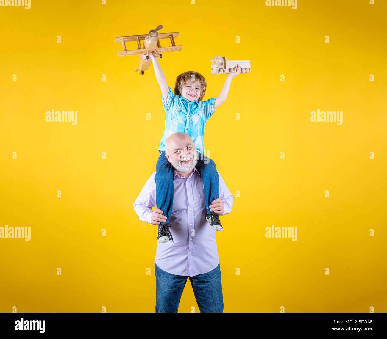 Grandfather and grandson piggyback ride with plane and wooden toy truck ...