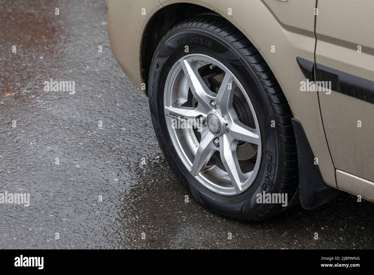 Car wheel riding on wet asphalt road in city. Side view of modern ...