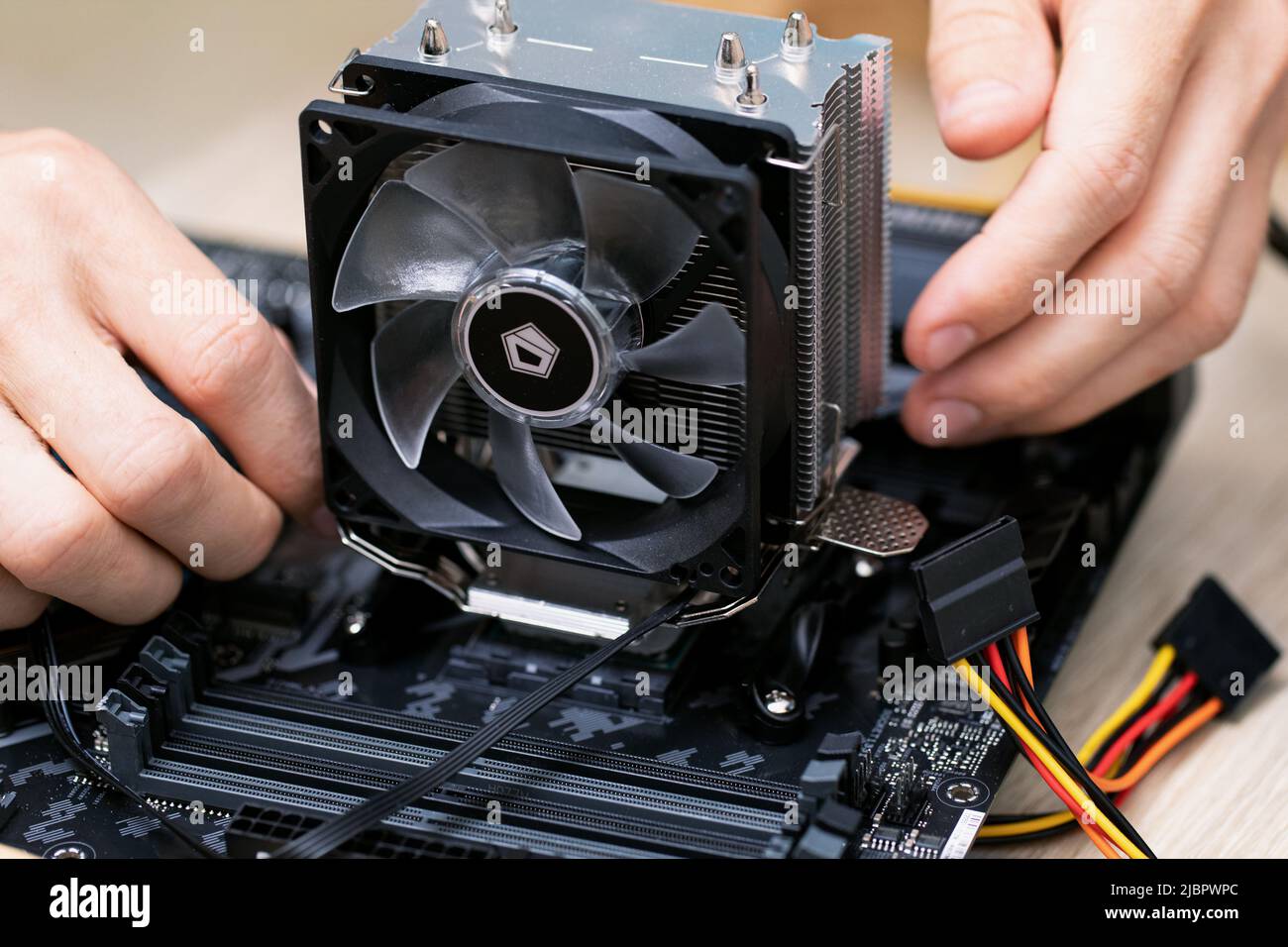 Technician man installs aluminum air-cooled heatsink on desktop CPU ...