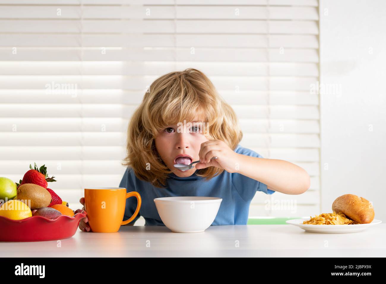 Child in the kitchen at the table eating vegetable and fruits during ...