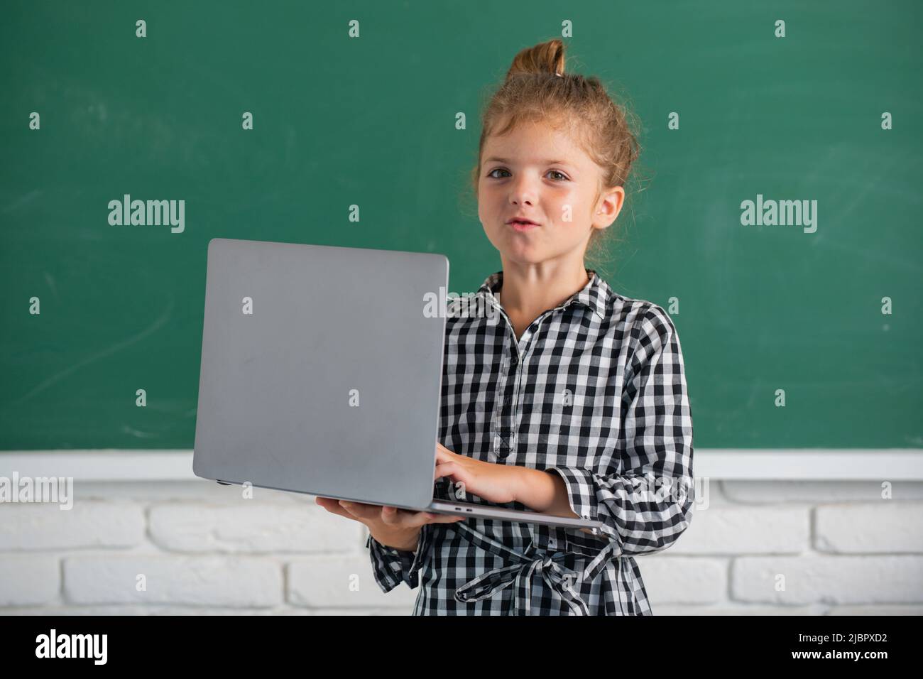 Portrait of attractive cheerful pupil girl using laptop. Kids education ...