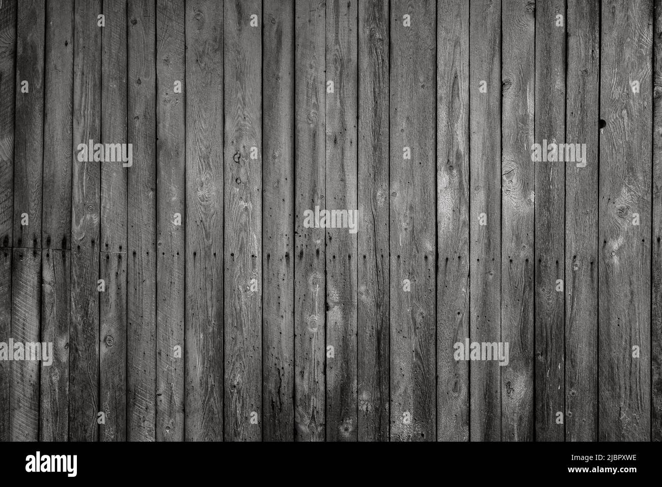 Front view of an old, weathered and dark wooden wall in black and white ...