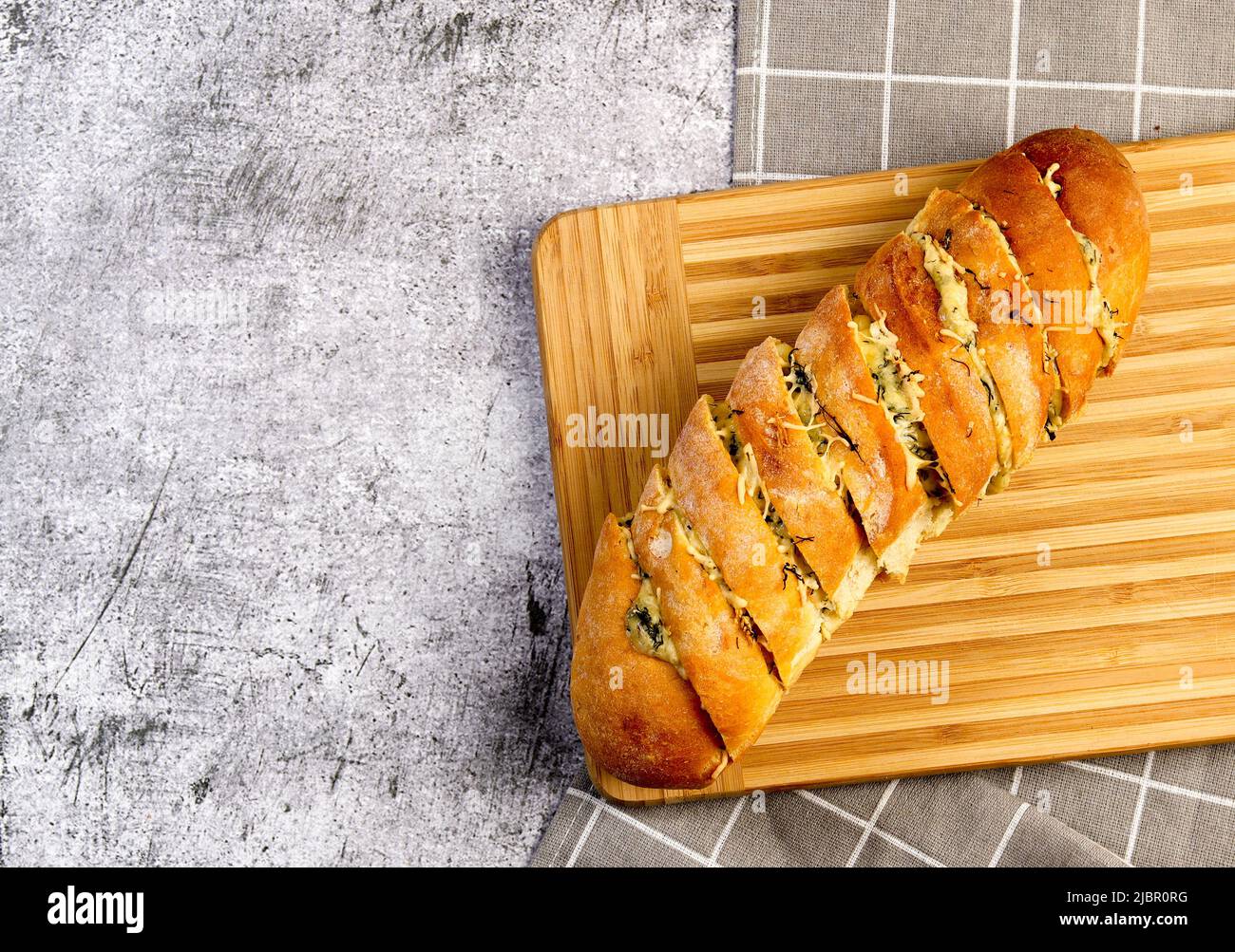 Cheesy Stuffed Garlic French Bread on a rectangular cutting wooden ...