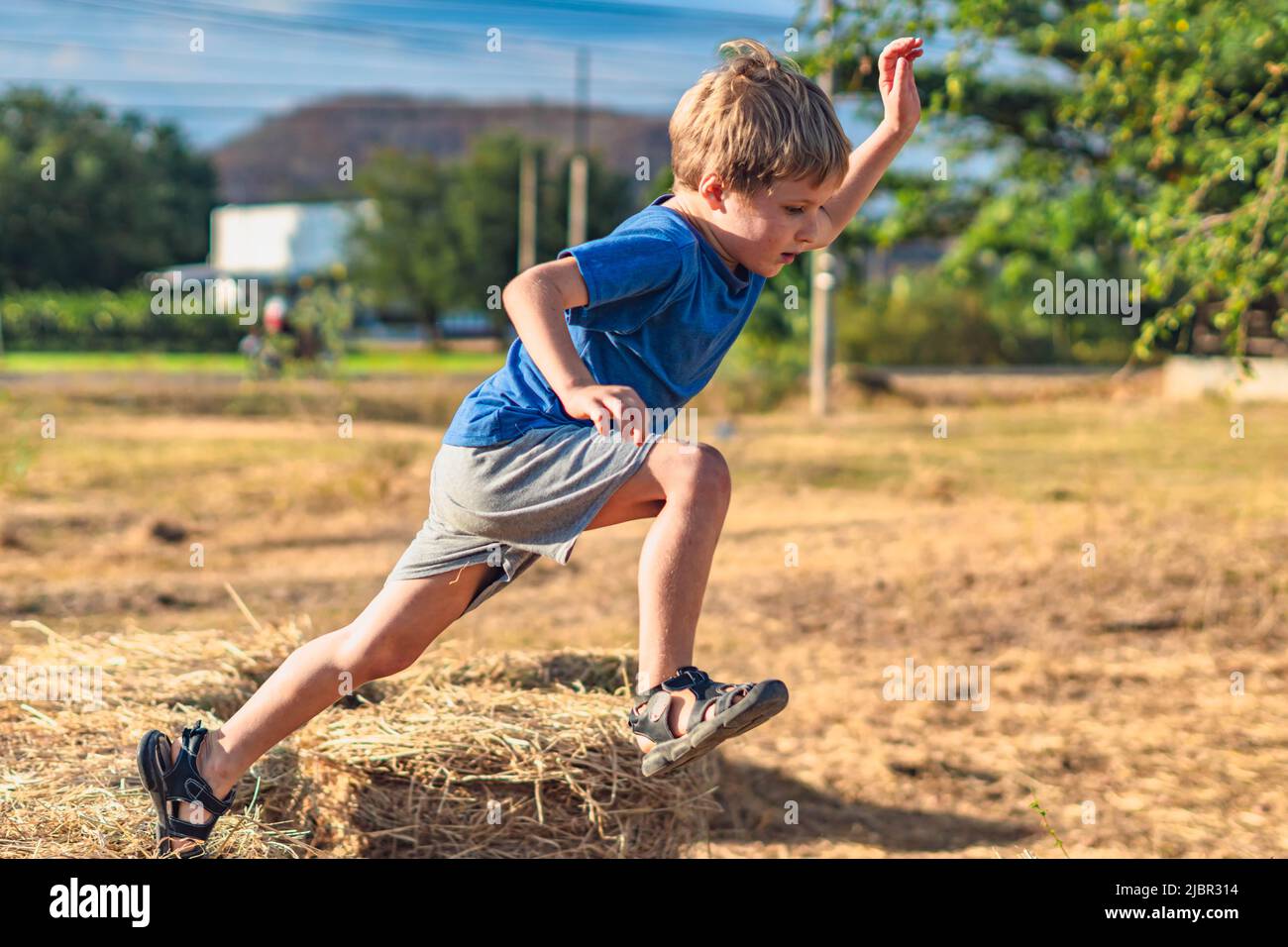 Side view Boy want jumping on haystack bales hay, frozen motion in air ...