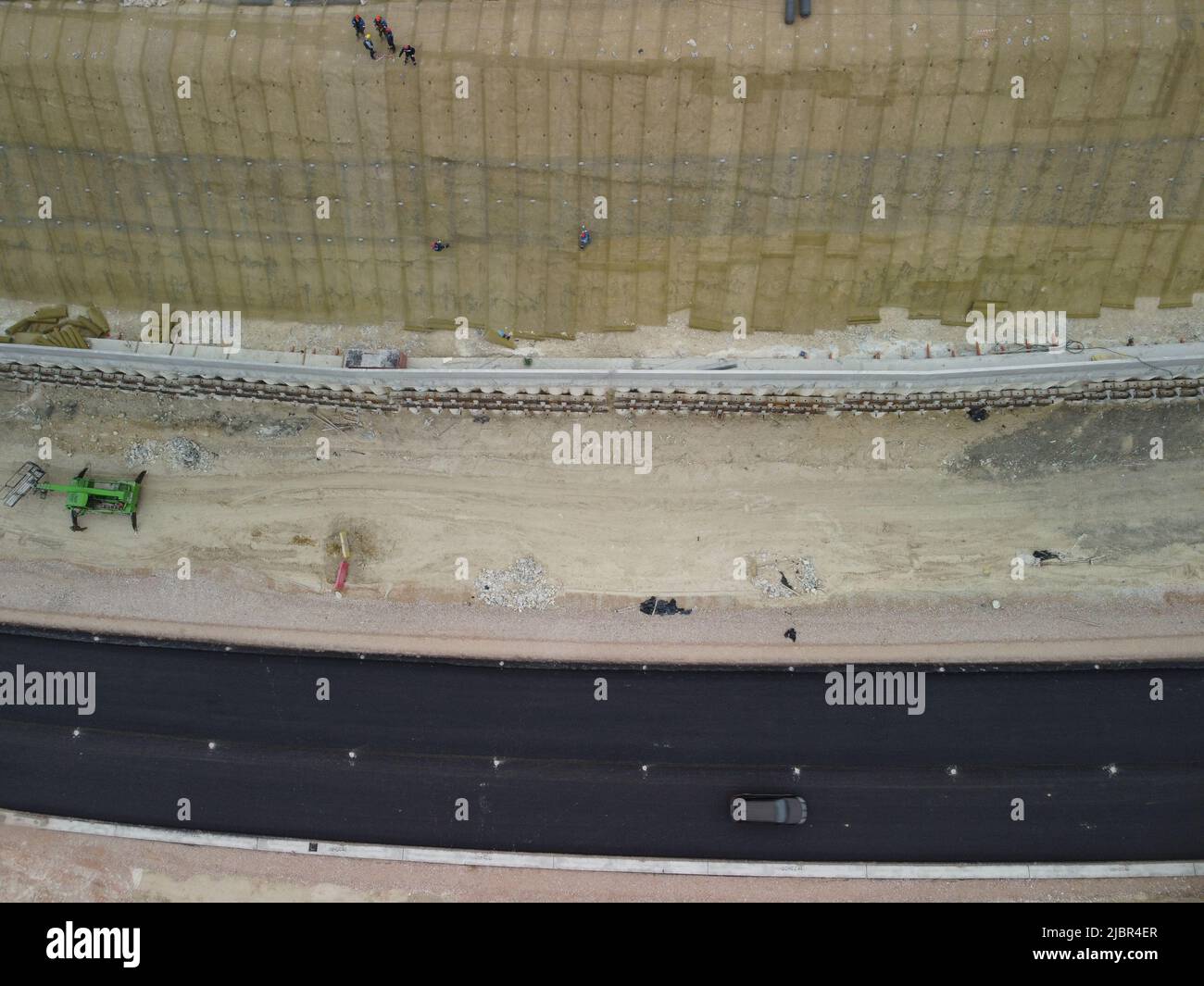 Workers reinforce the slope over the new road. Road construction in ...