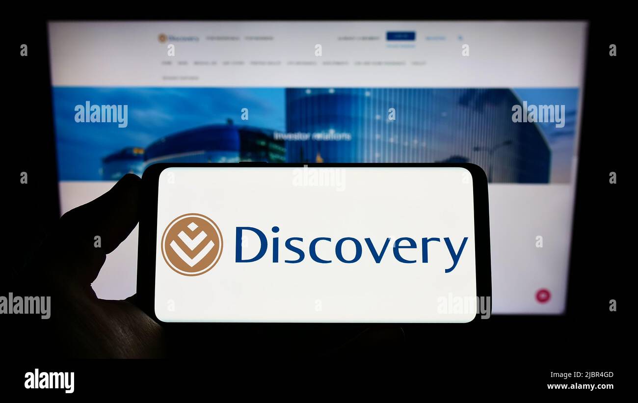 Person holding smartphone with logo of South African company Discovery ...