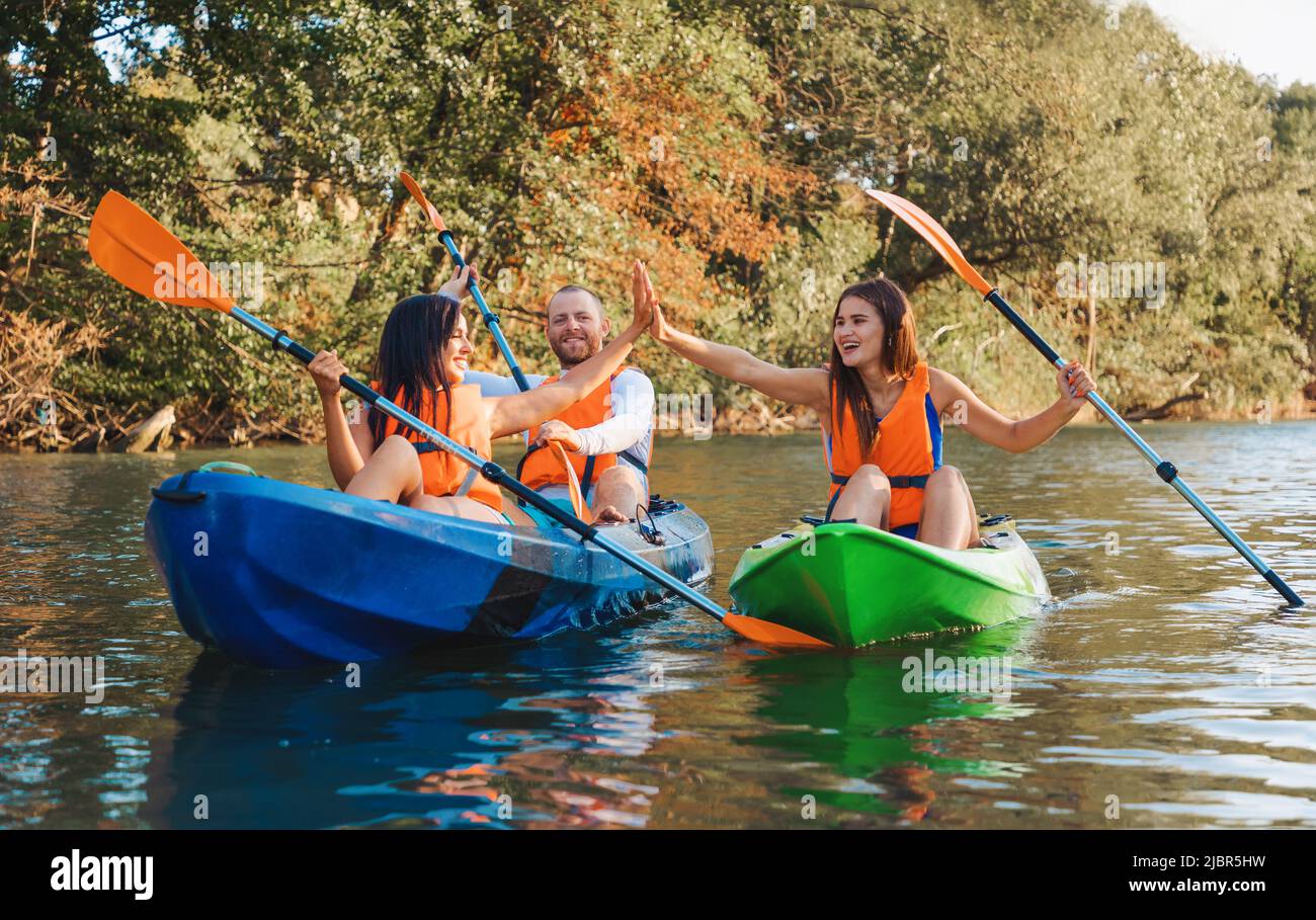 Kayaking at th river. A group of happy friends are high five sitting in ...