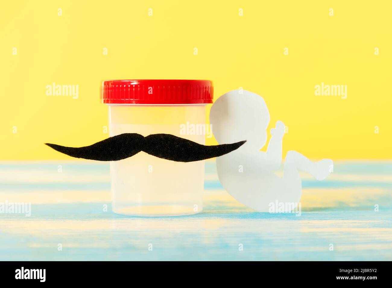 Test-tube with sample of sperm with felt moustache and paper embryo ...